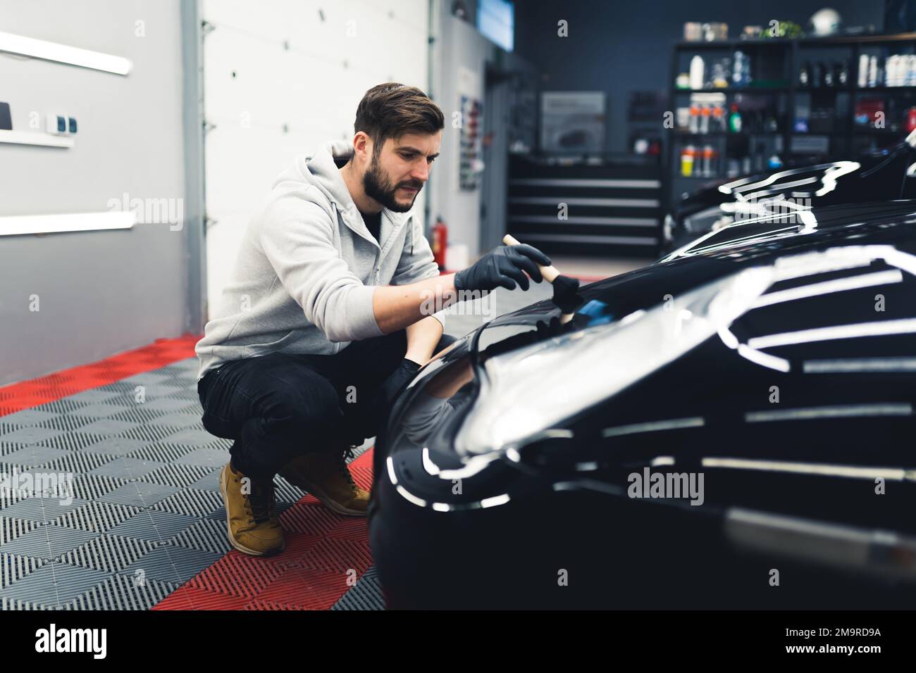 Adult male detailing expert using detailing brush to clean the hood and ...