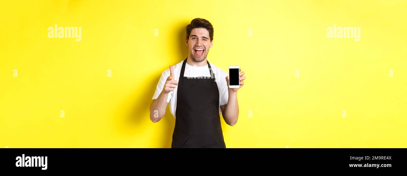 Happy waiter showing mobile screen and thumb up, recommending cafe ...
