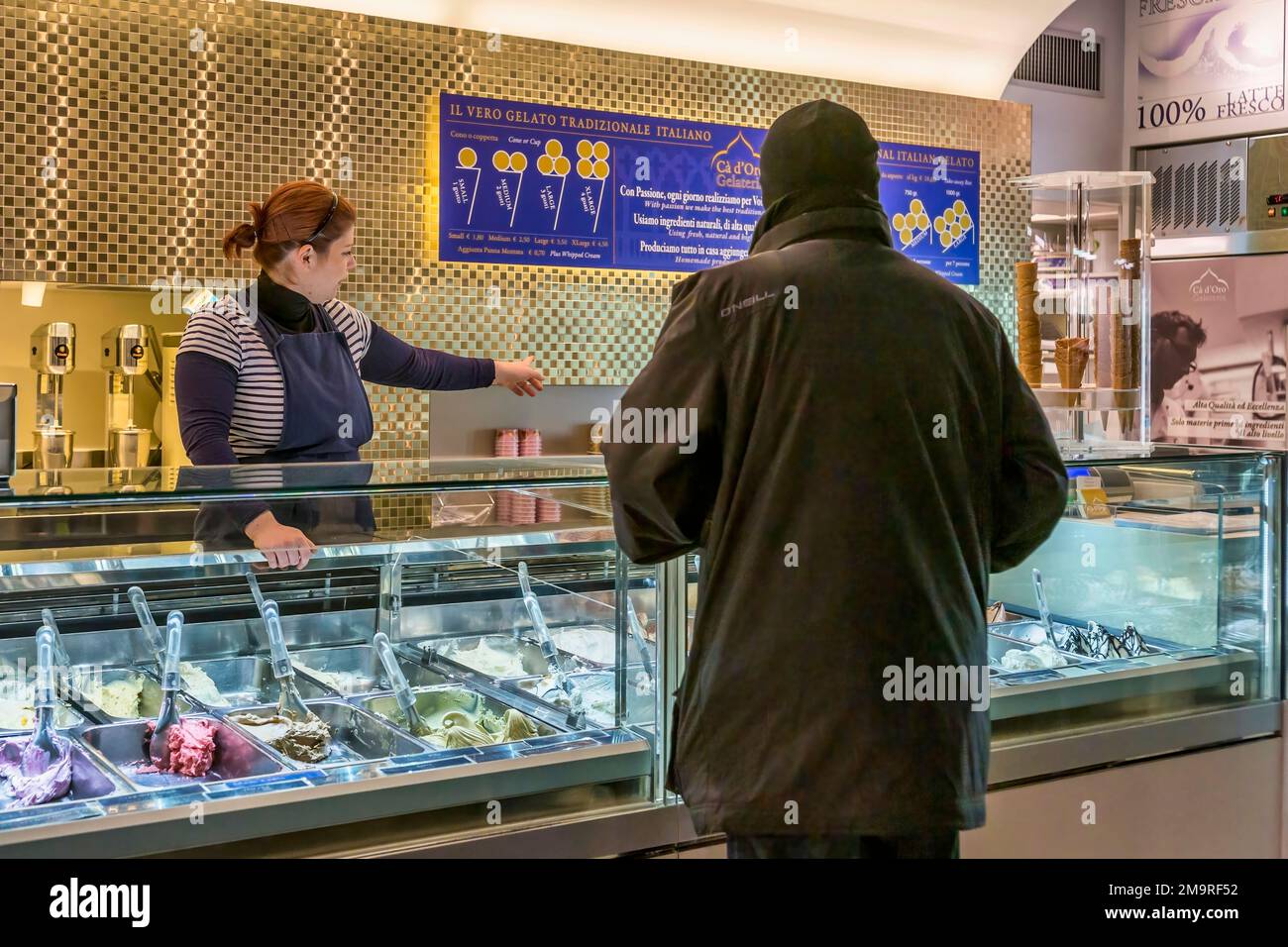 A saleswoman offers gelato to a customer in a sweet shop on a ...