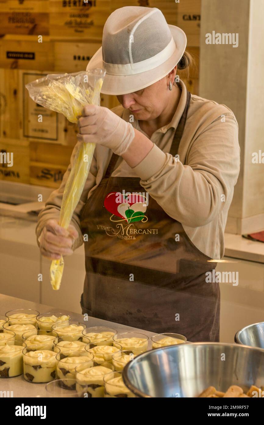 A pastry cook prepares desserts in the window of a shop on a pedestrian ...