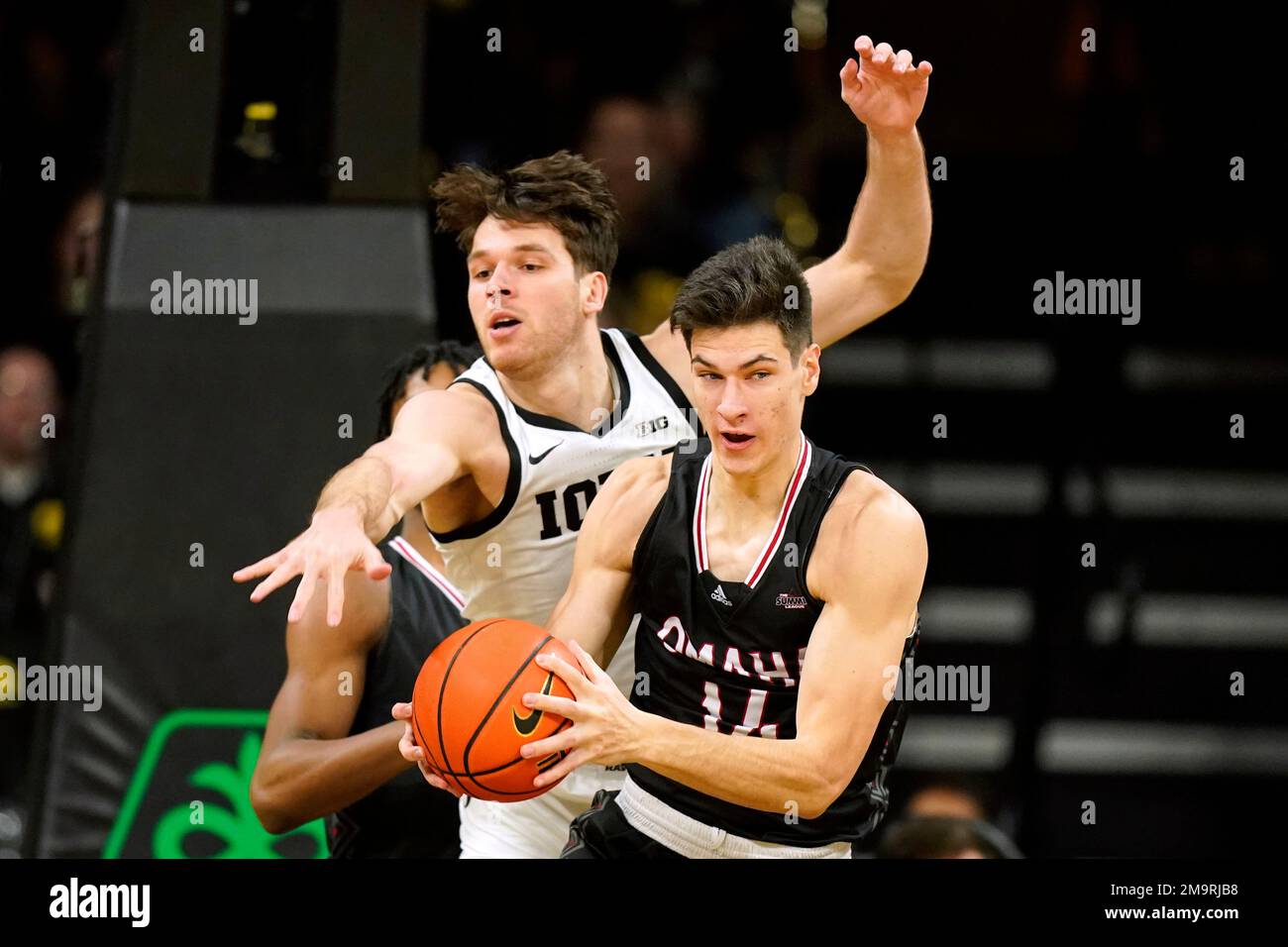 Omaha center Dylan Brougham (14) grabs a rebound ahead of Iowa forward ...