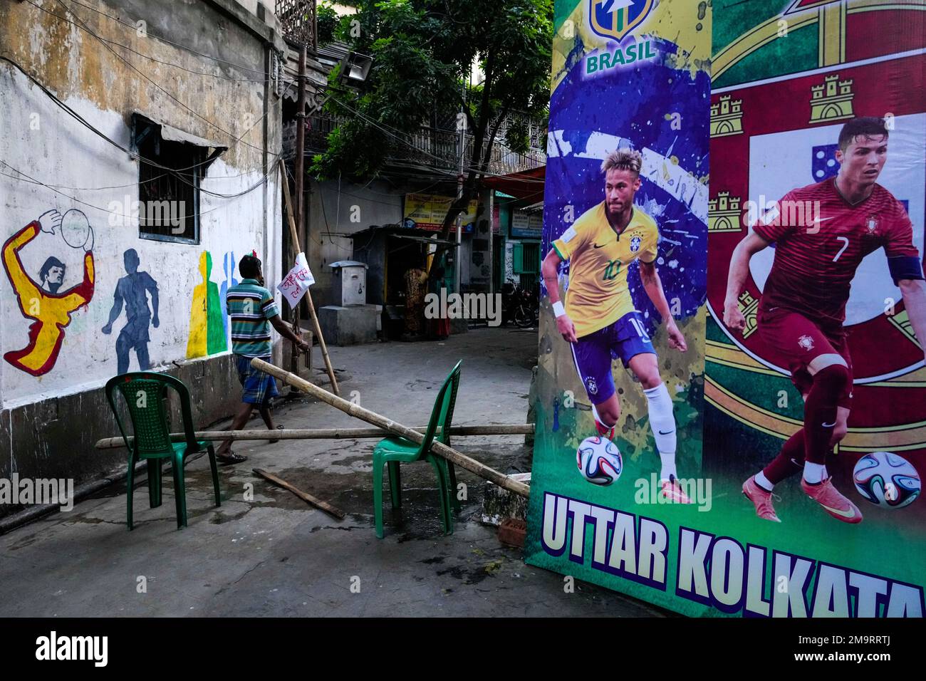 A man walks beside an unfinished football graffiti in a blocked alley ...