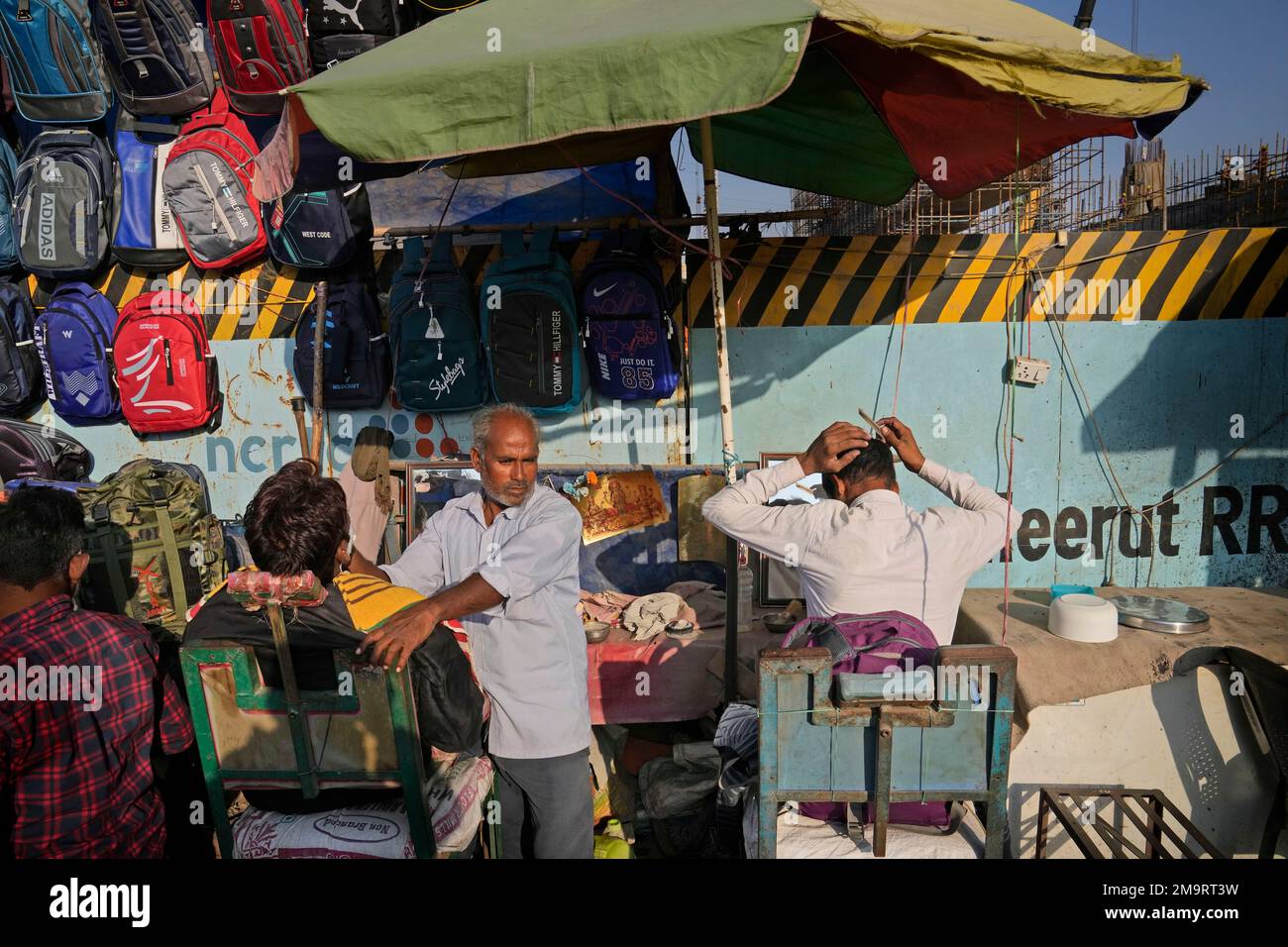 A street barber gives a shave to a customer at a busy crossing in New ...