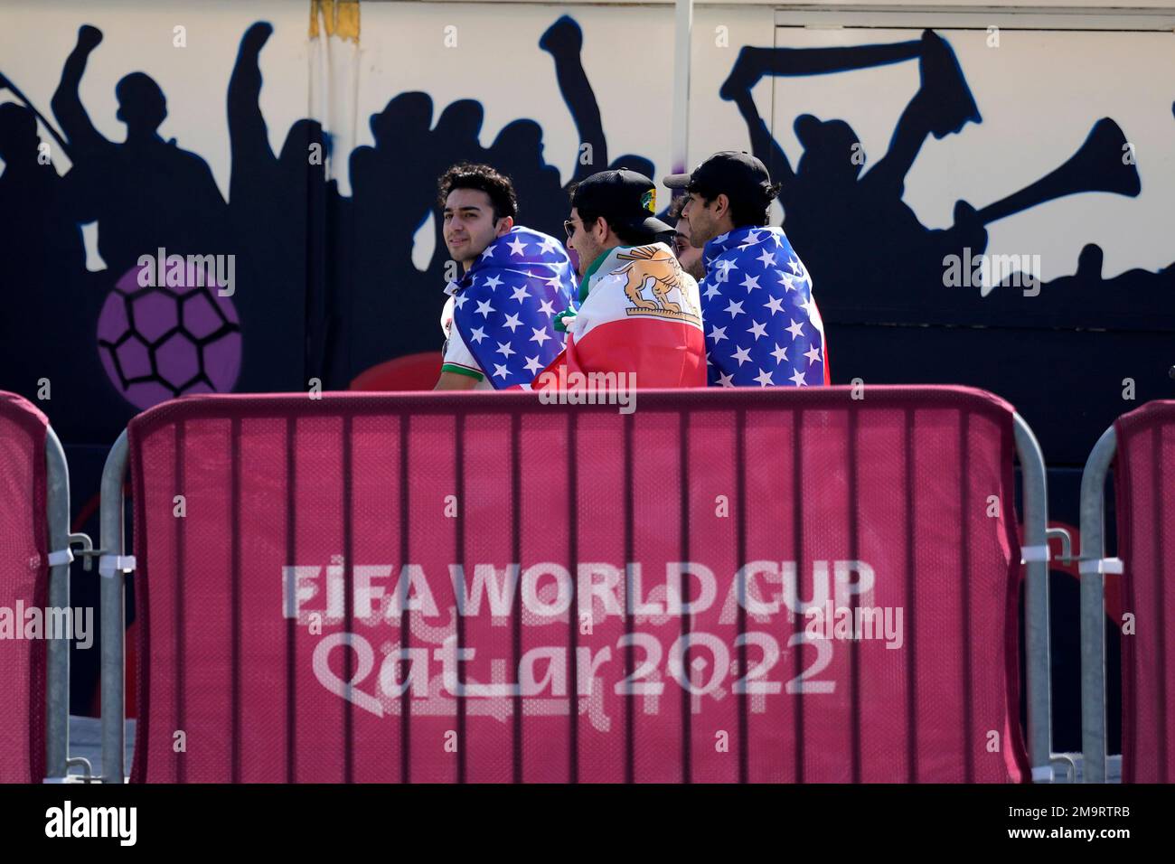 Soccer fans walk on a street along the wall painting for Qatar 2022 ...