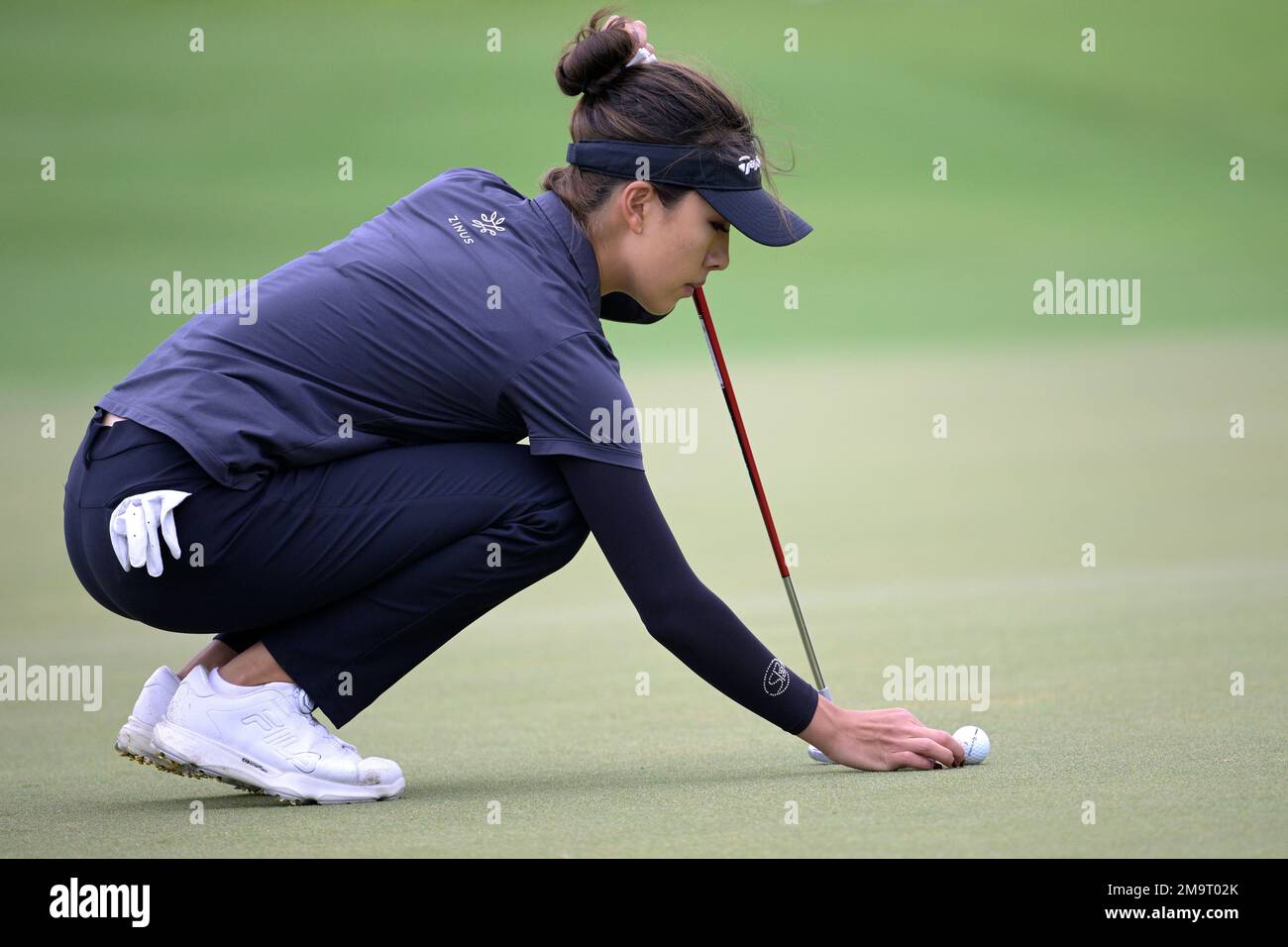 Muni He, of China, lines up a putt on the third green during the final ...