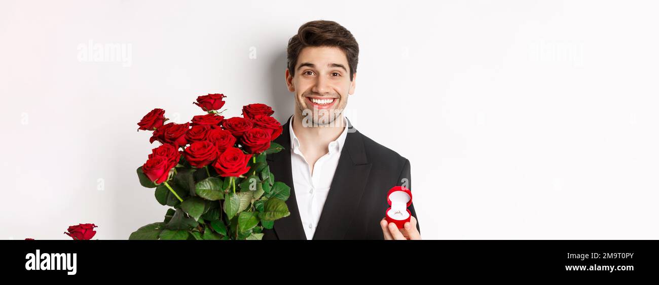 Close-up of attractive man in suit, holding bouquet of roses and ...