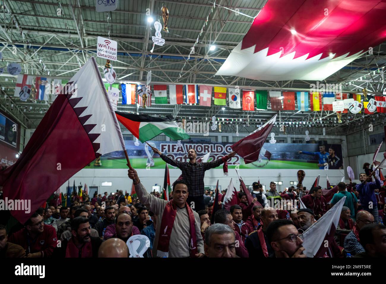 Palestinian soccer fans wave Qatari and Palestinian flags as they watch ...