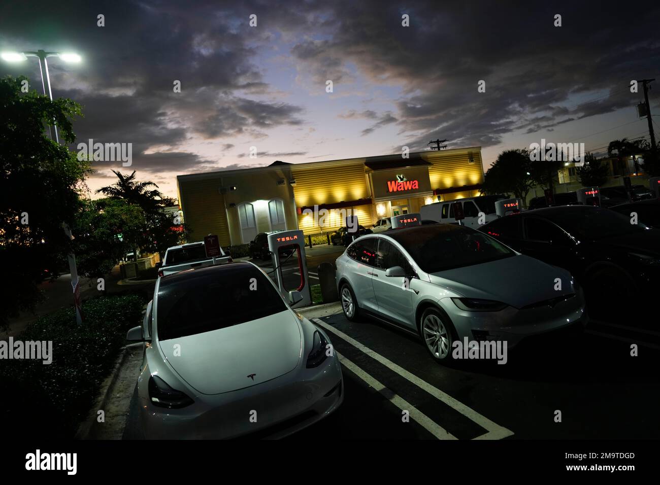 Tesla drivers charge their cars at a Tesla Supercharger station ...