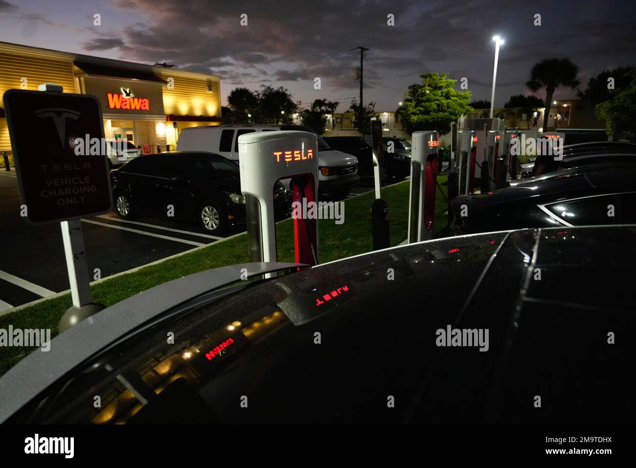 Tesla drivers charge their cars at a Tesla Supercharger station ...