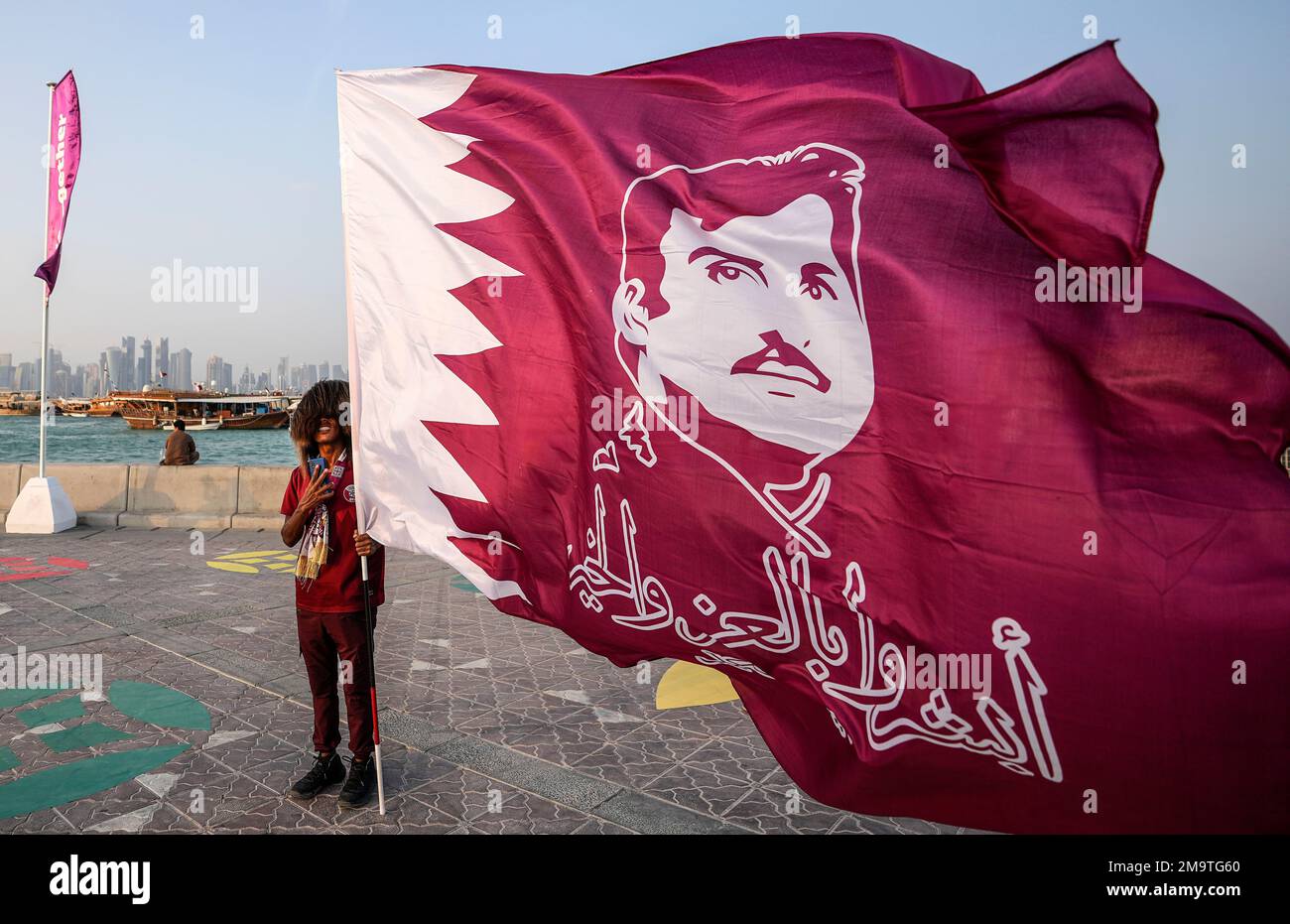 A Qatar fan holds a flag showing the Emir of Qatar Tamim bin Hamad Al ...