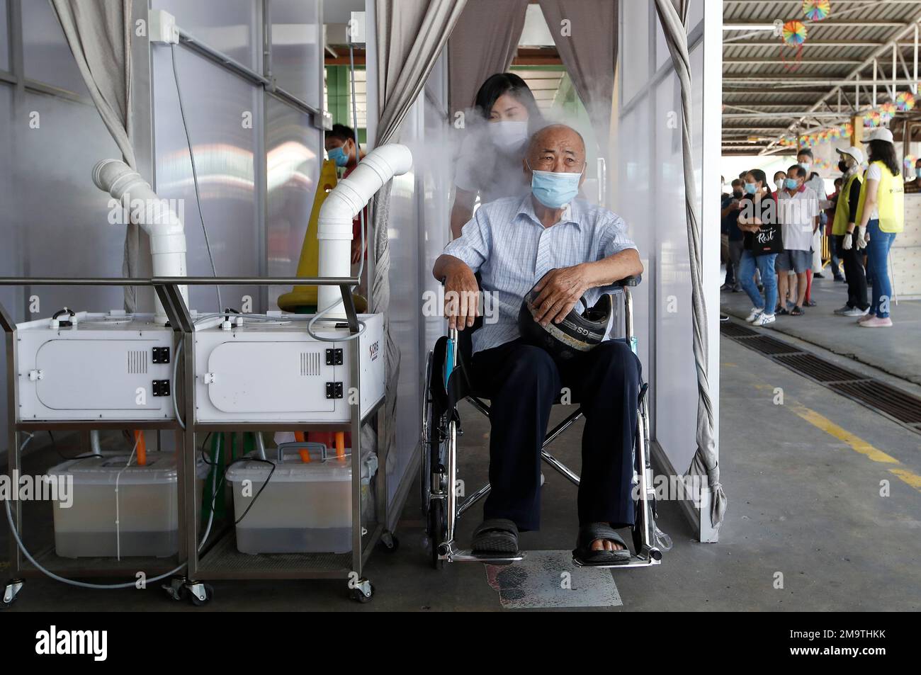 An elderly voter on wheel chair sanitises before casting his ballot for ...