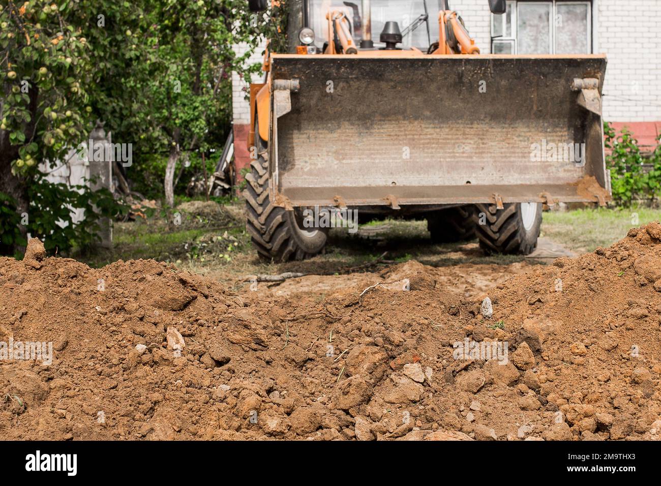 Excavator or bulldozer bucket flattens the ground or road in the ...