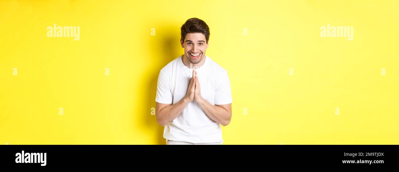 Handsome guy saying thank you, bowing and holding hands in namaste ...
