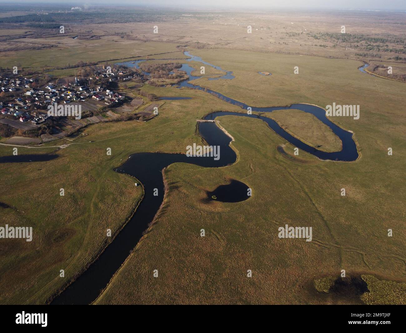 aerial view of a beautiful winding river flows among the fields, which ...