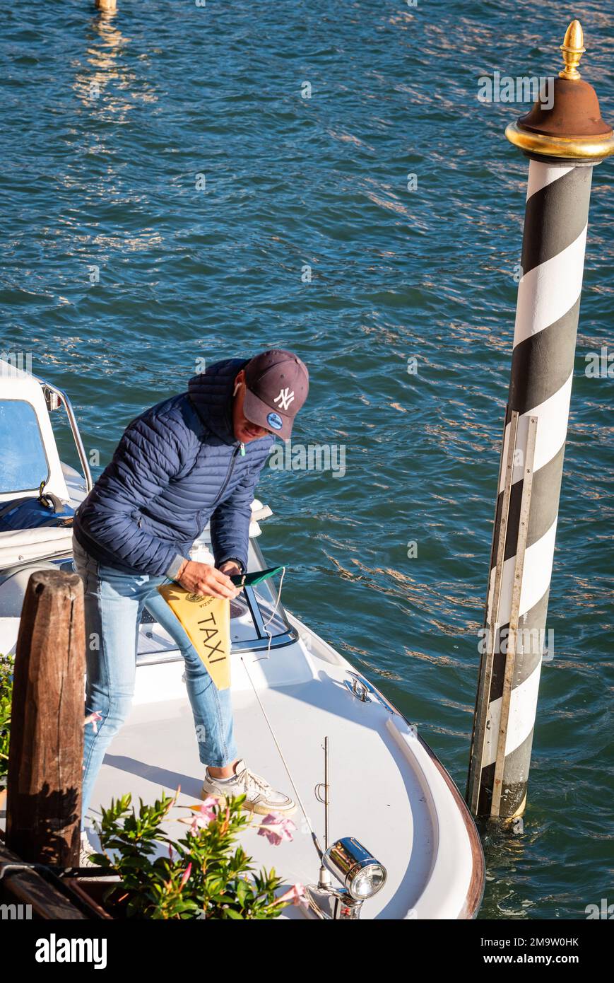 A taxi boat driver sets up his flags in the morning while moored near a ...