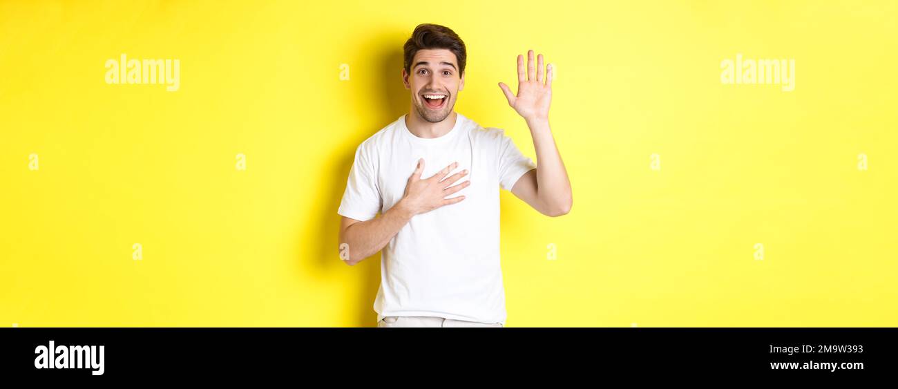 Happy guy making promise, holding hand on heart, swearing to tell truth ...