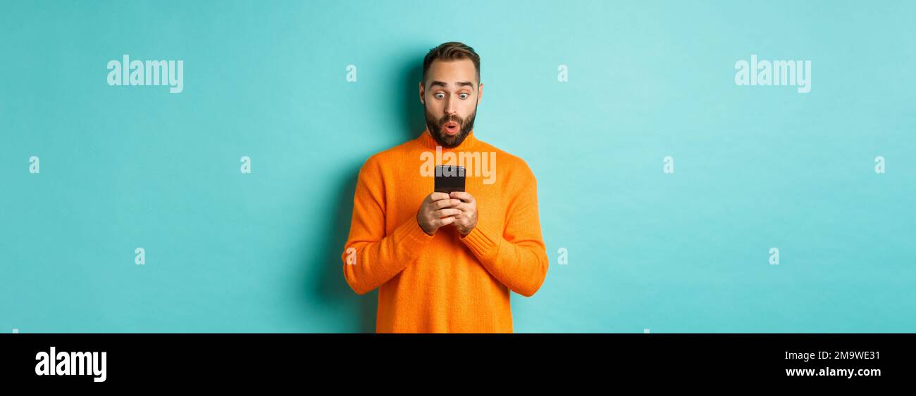Image of man reading message with surprised face, standing amazed over ...