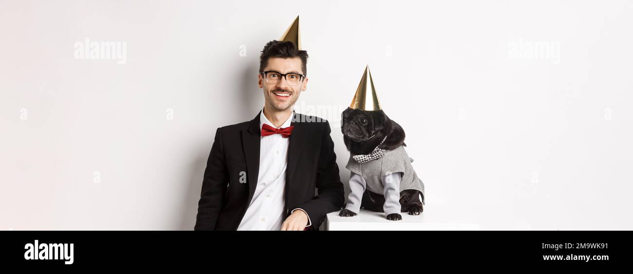 Image of handsome young man celebrating birthday with cute black pug in ...