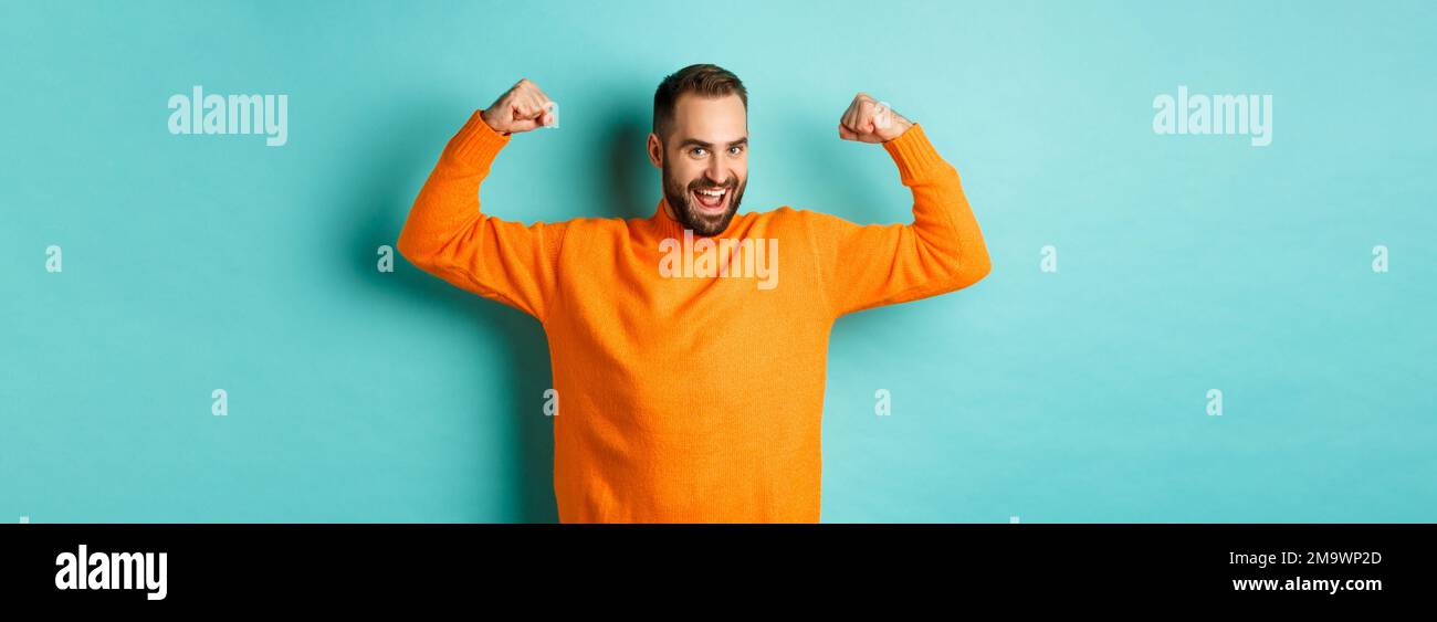 Young and strong man looking confident, flex biceps and show-off muscle ...