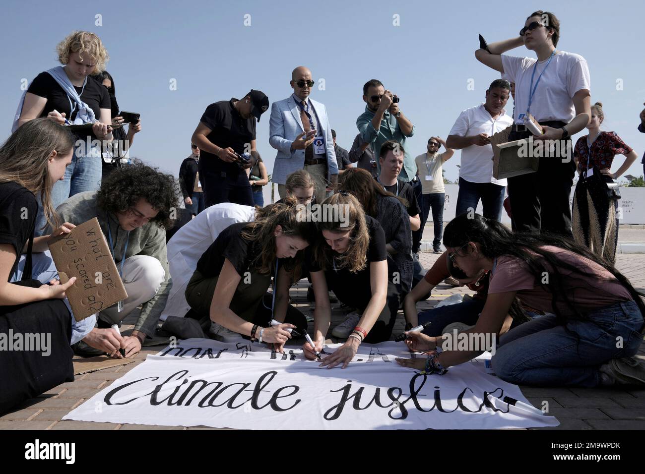 Climate activists work on a sign that reads "don't be scared of climate ...