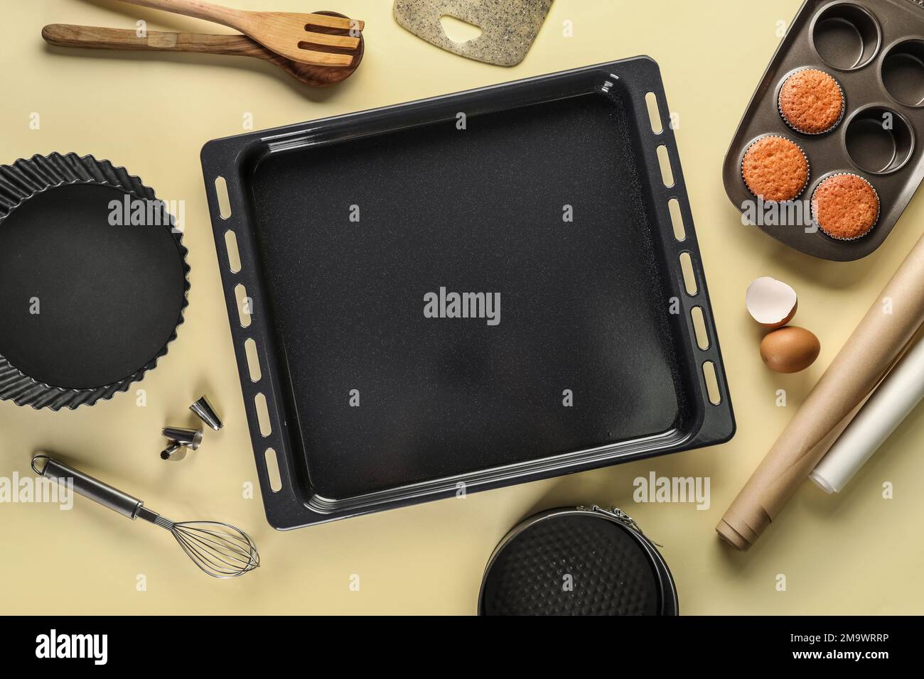 Baking trays with muffins, eggs and utensils on beige background Stock ...