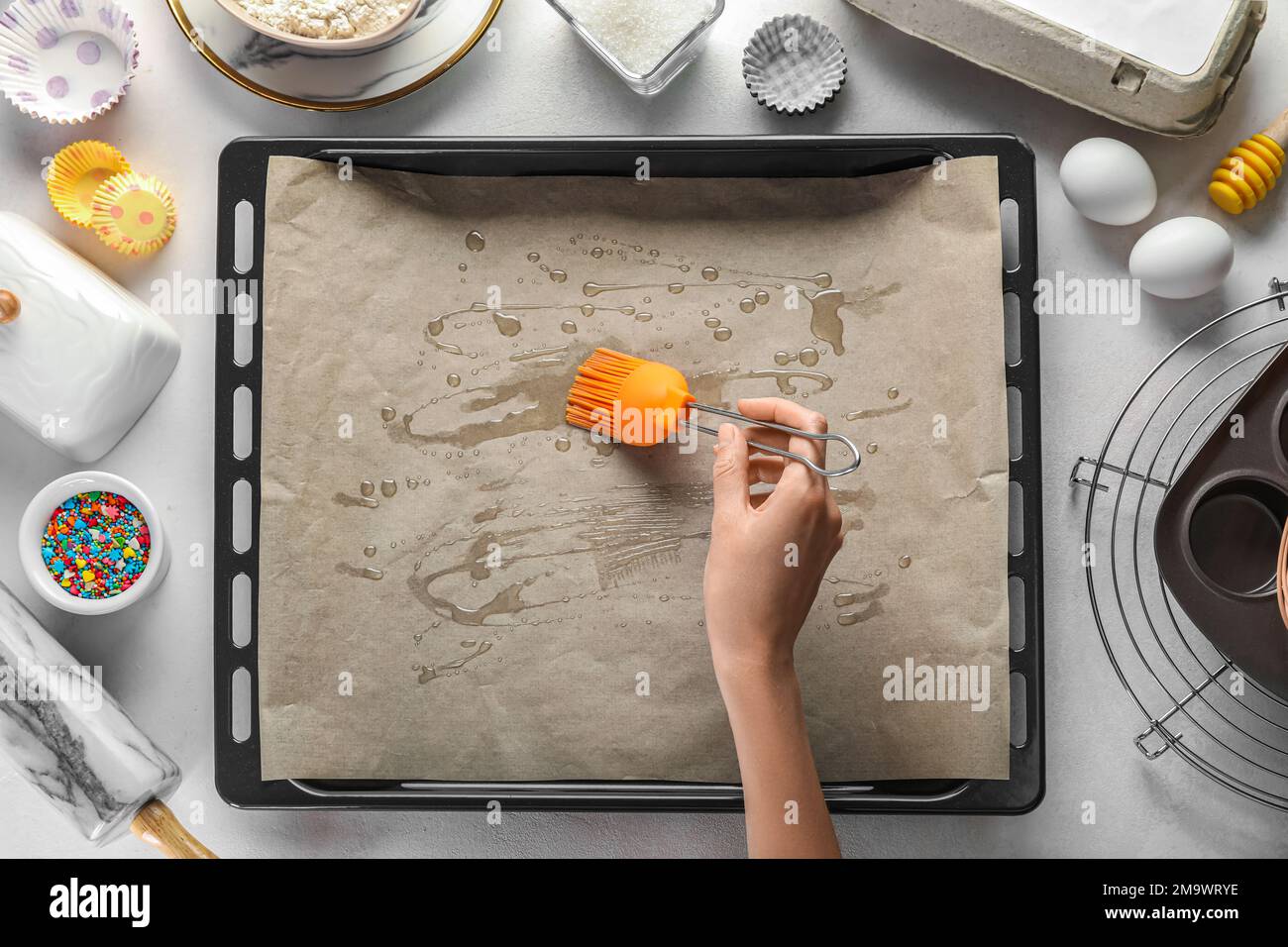 Woman greasing parchment paper with oil on white background Stock Photo ...