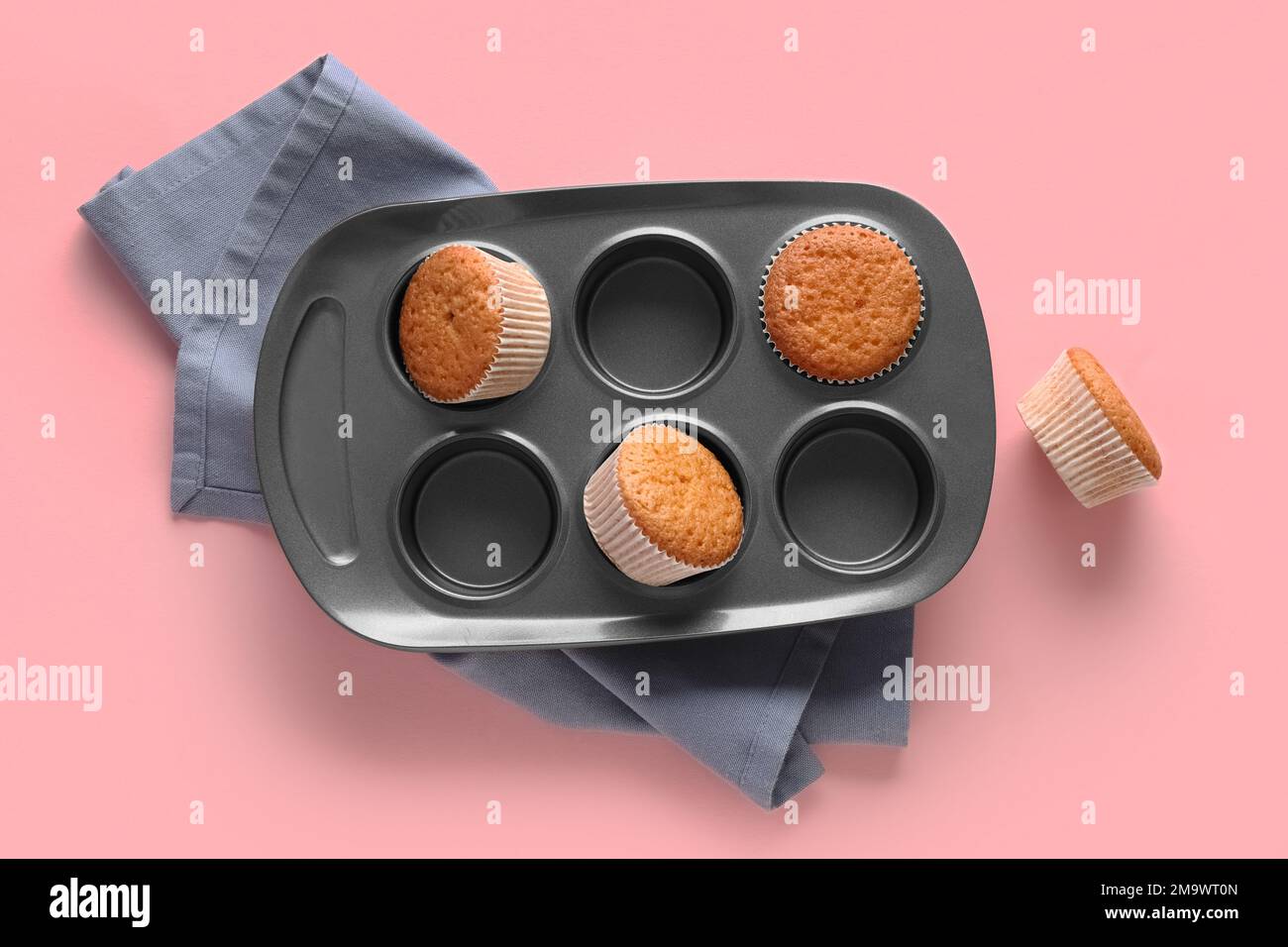 Baking tray with muffins and napkin on pink background Stock Photo - Alamy