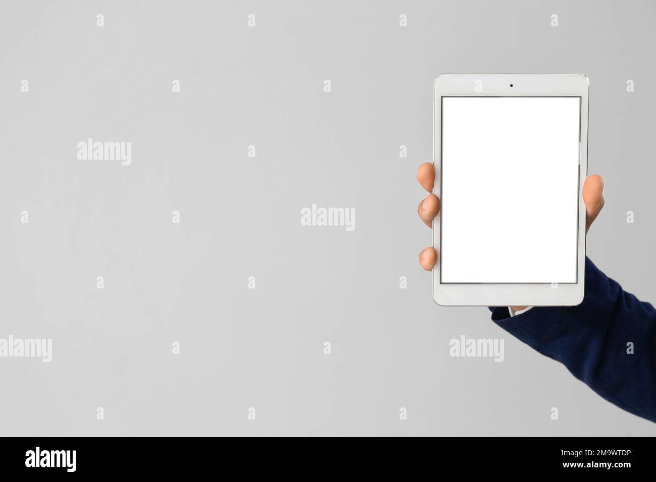 Young businessman with tablet computer on light background, closeup ...