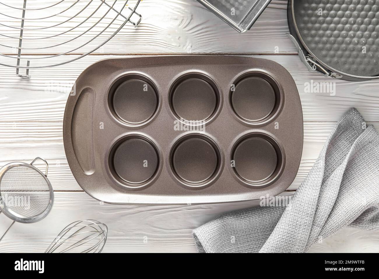 Muffin tray and kitchen utensils on light wooden background Stock Photo ...