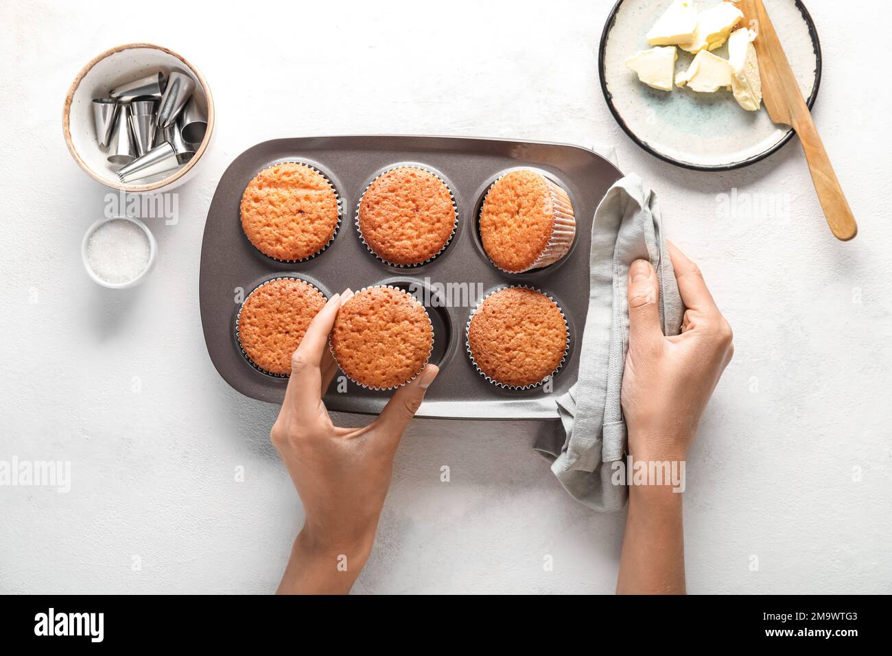 Female hands with tasty muffins, ingredients and piping tips on light ...