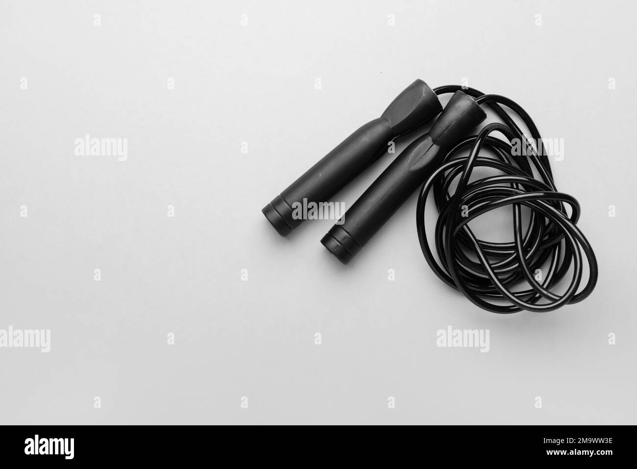 Black skipping rope on light background Stock Photo - Alamy