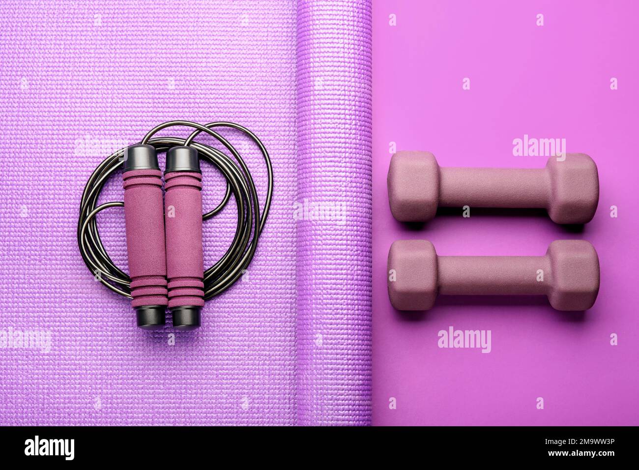 Skipping rope with fitness mat and dumbbells on violet background Stock ...