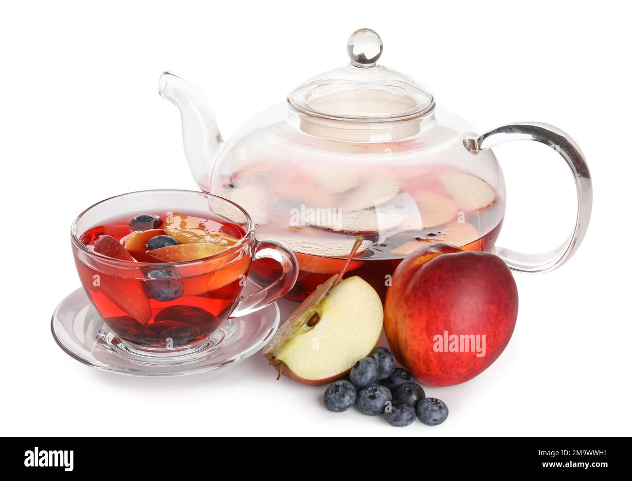 Glass cup of fruit tea with blueberries, apple, peach and teapot on ...