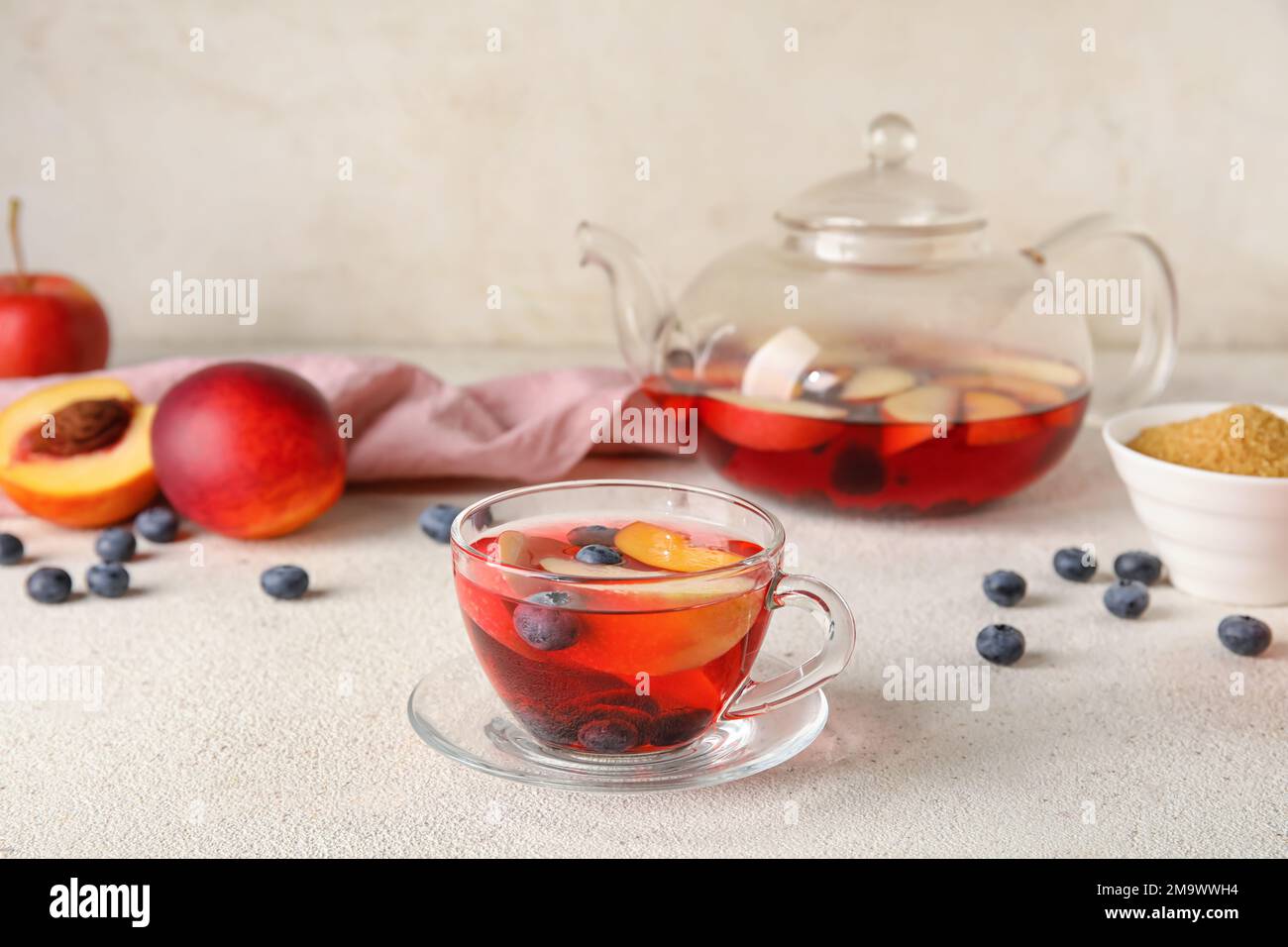 Glass cup of fruit tea with blueberries, apple and peach on light ...