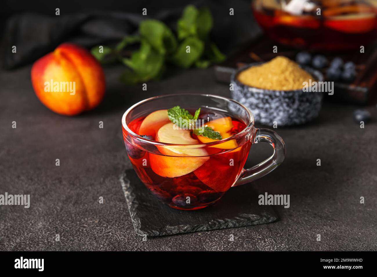 Glass cup of fruit tea with blueberries, apple and peach on dark ...