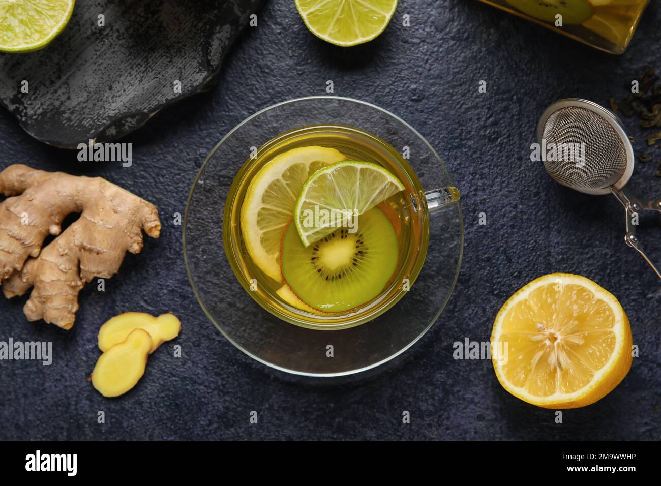 Glass cup of fruit tea with kiwi, lemon, lime and ginger on dark ...