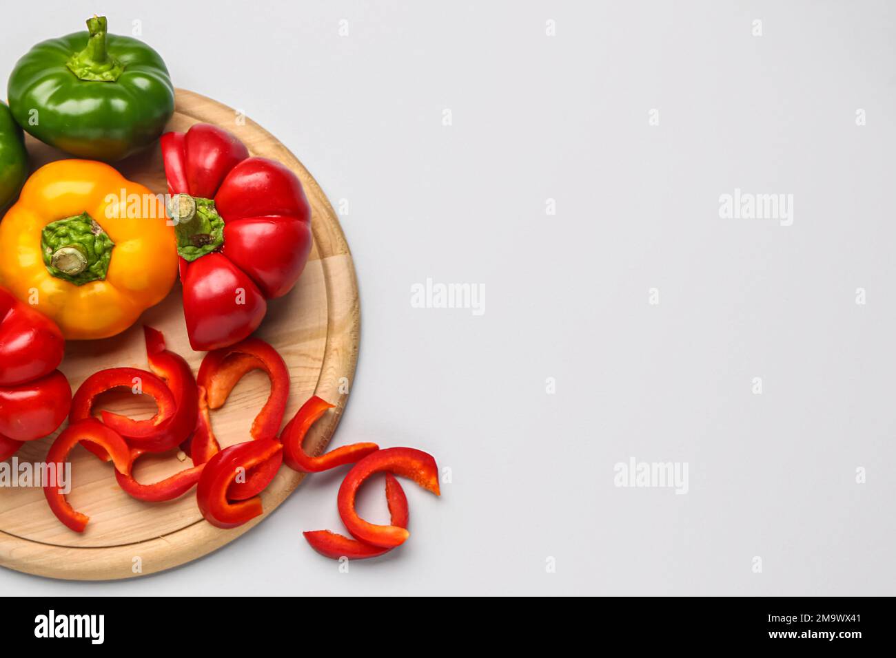 Wooden board with bell peppers on white background Stock Photo - Alamy