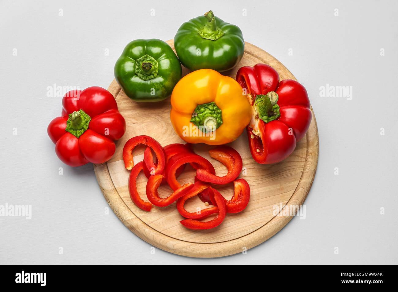 Wooden board with bell peppers on white background Stock Photo - Alamy