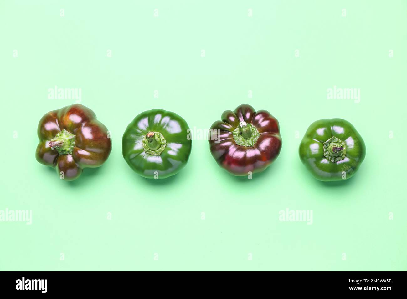 Row of bell peppers on color background Stock Photo - Alamy