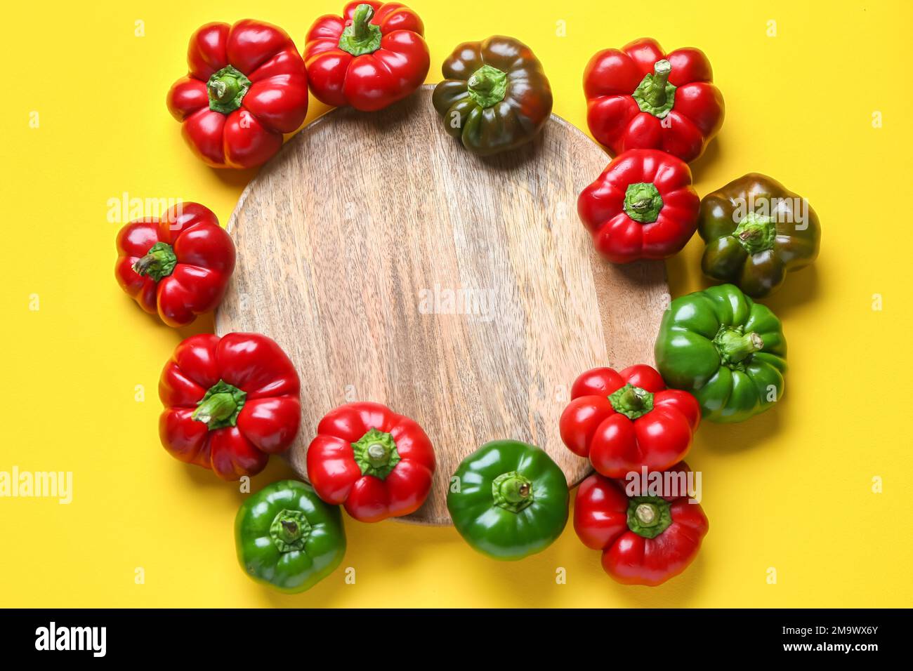 Composition with fresh bell peppers and wooden plate on yellow ...