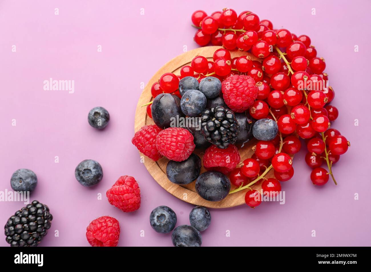 Wooden board with fresh ripe berries on color background Stock Photo ...
