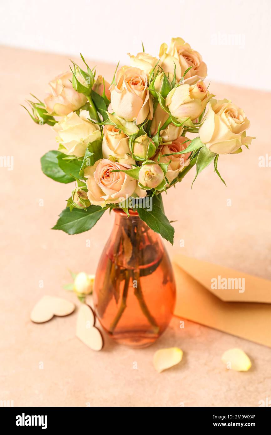 Vase with beautiful rose flowers and envelope on color table Stock ...