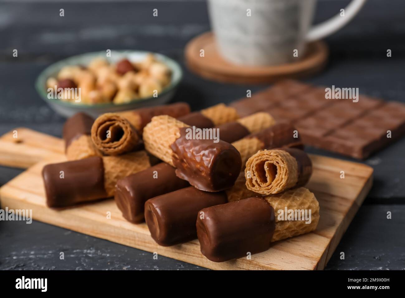 Board of delicious wafer rolls, chocolate bar, bowl of hazelnuts and ...