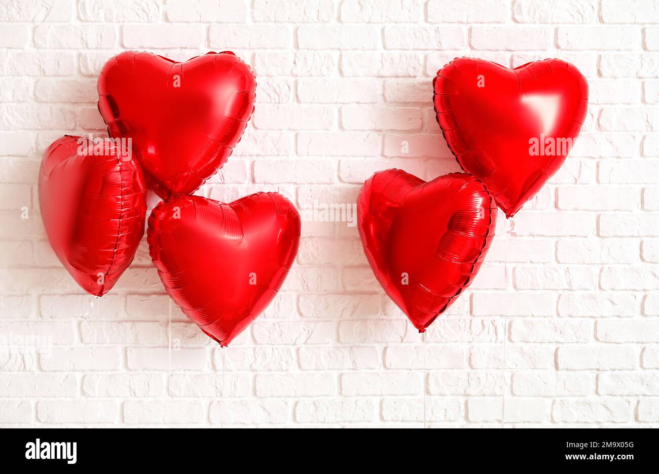 Heart shaped balloons for Valentine's Day on white brick background ...