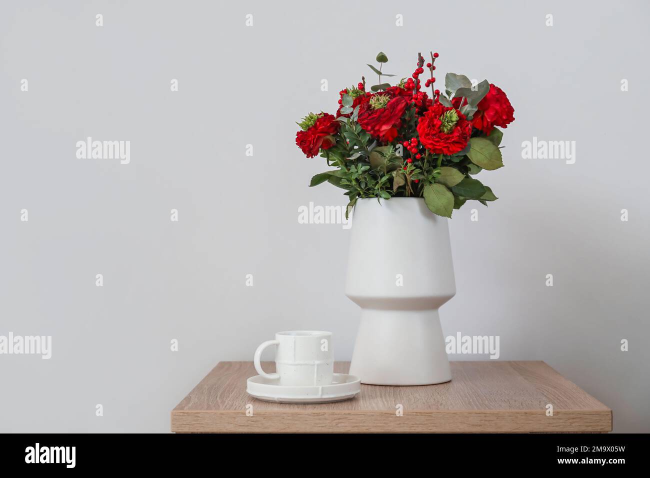 Vase with flowers for Valentine's Day and cup of coffee on table near ...