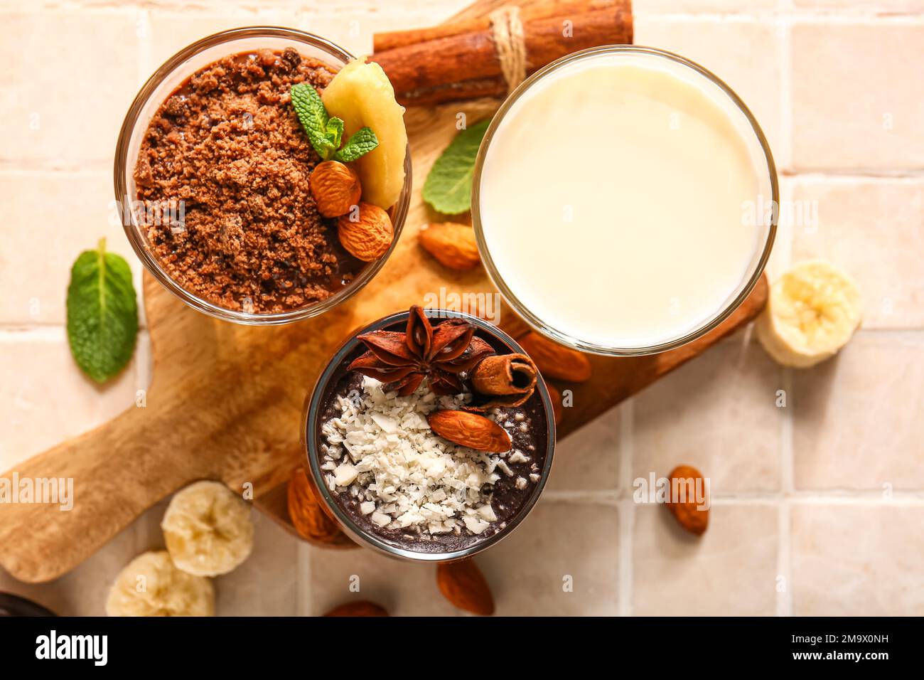 Board with glasses of delicious chocolate pudding, cinnamon, almond and ...