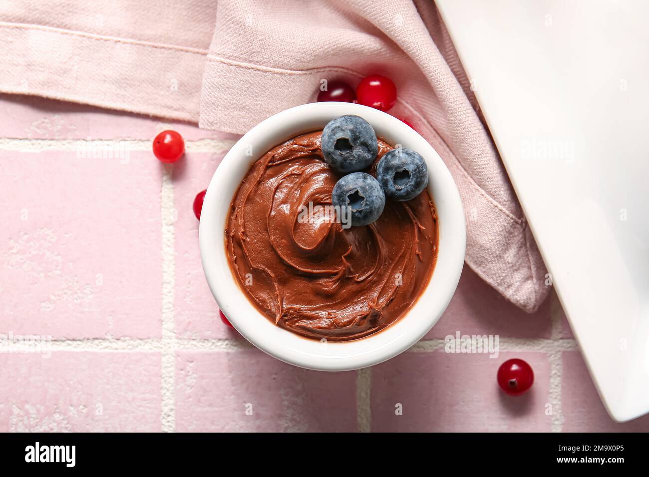 Bowl of delicious chocolate pudding with blueberry on pink tile table ...