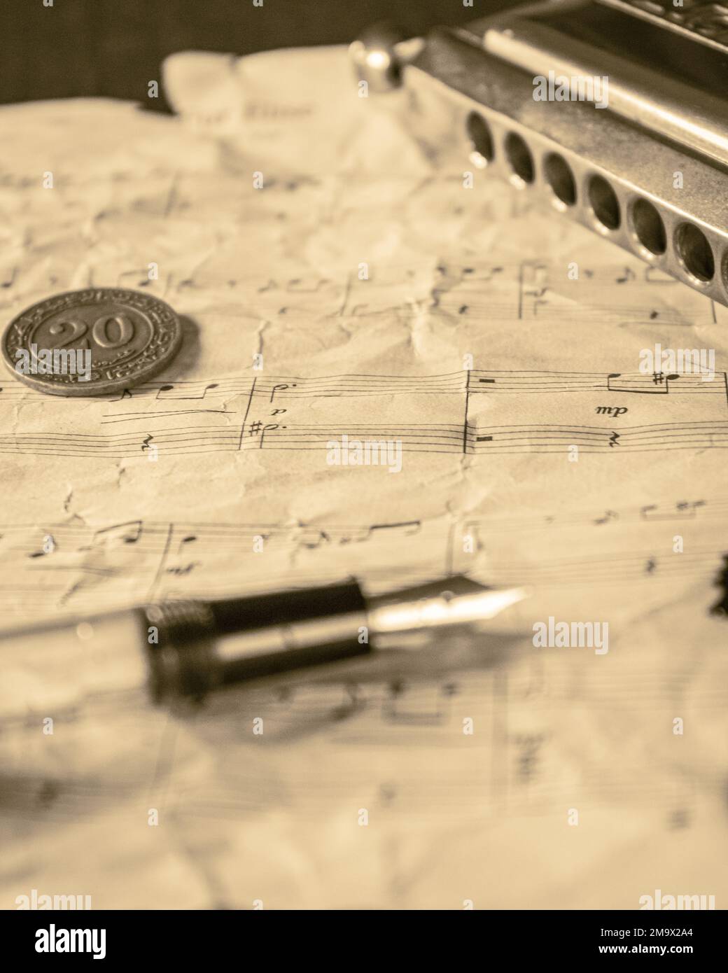A Harmonica copper coin and fountain pen on an old paper vintage music ...