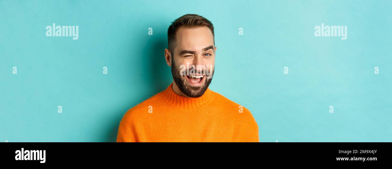 Handsome confident man winking at camera, smiling sassy, standing in ...