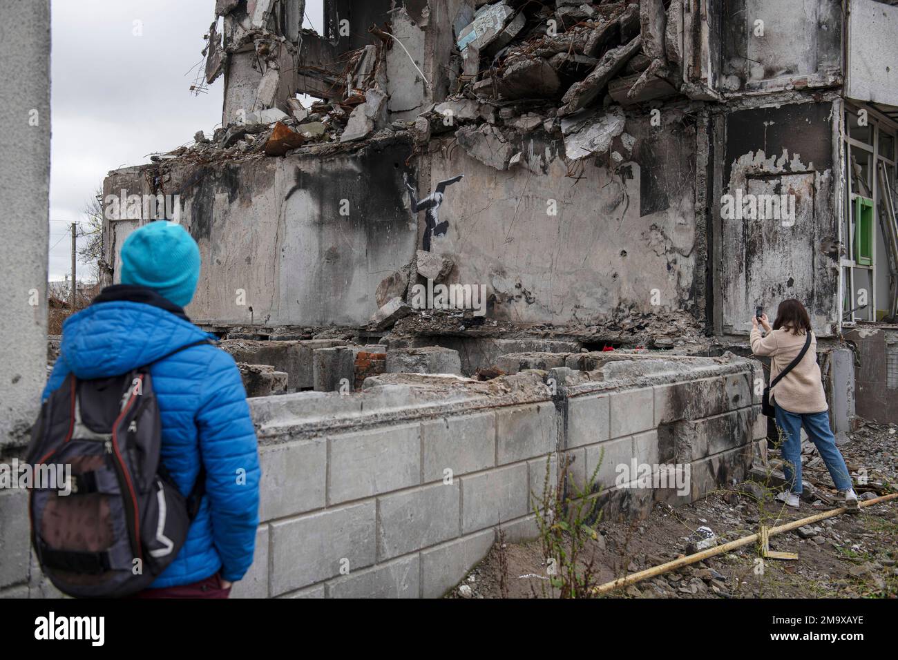 People look at a painting by British street artist Banksy on a building destroyed by fighting in ...